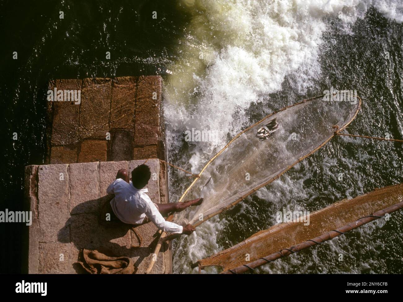 A man is fishing just adjacent to the barrage; gate of the ...
