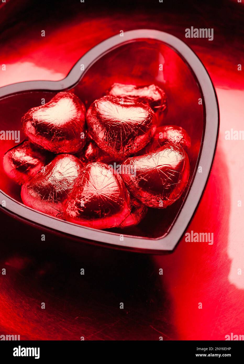 Small red chocolate hearts in heart-shaped glass bowl Stock Photo - Alamy