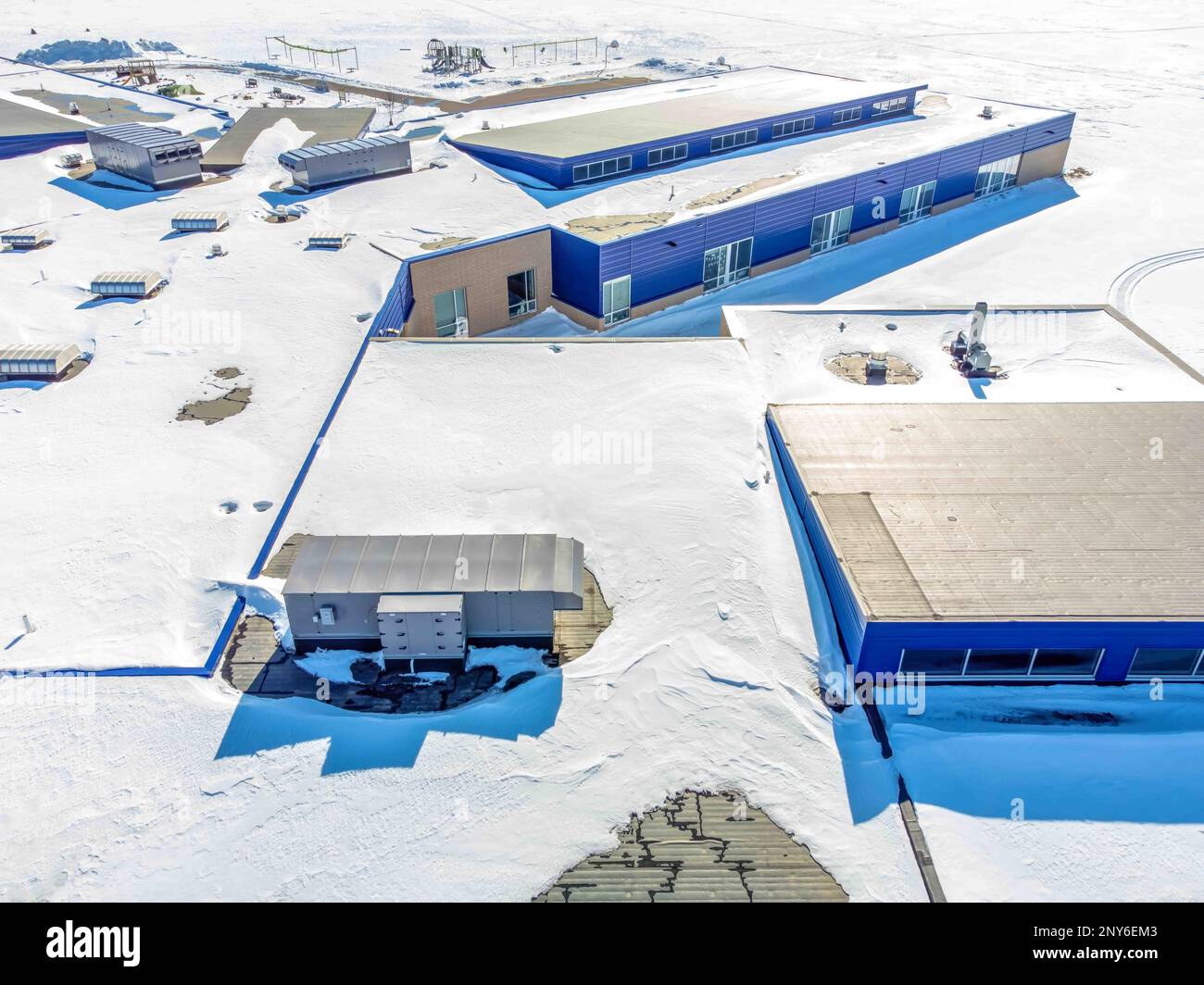 Elevated overhead drone view of a flat roofed building with snow load ...