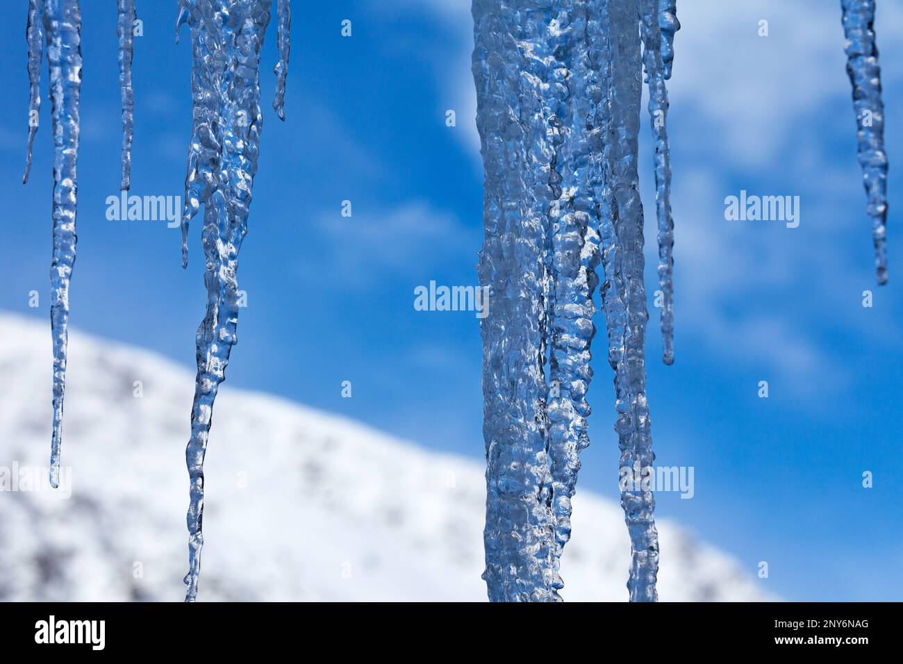 Close-up on ice stalactites formed at the bottom edge of a roof ...