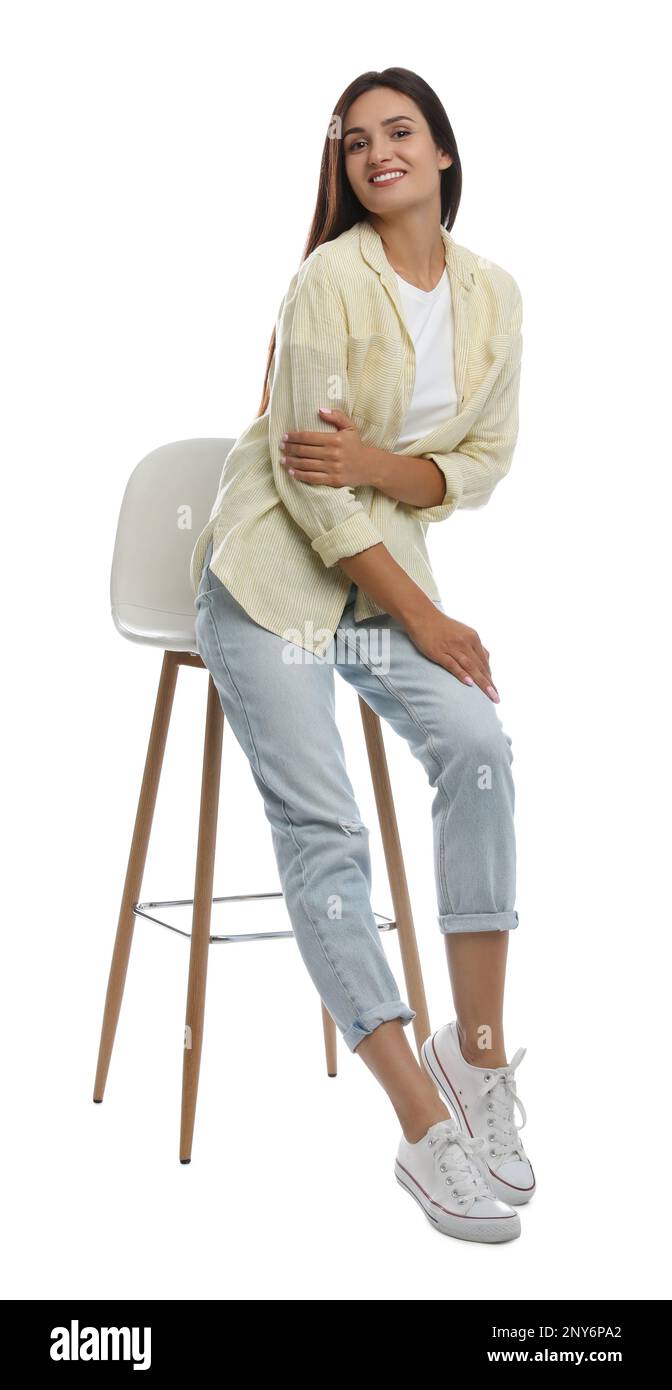 Beautiful young woman sitting on stool against white background Stock ...