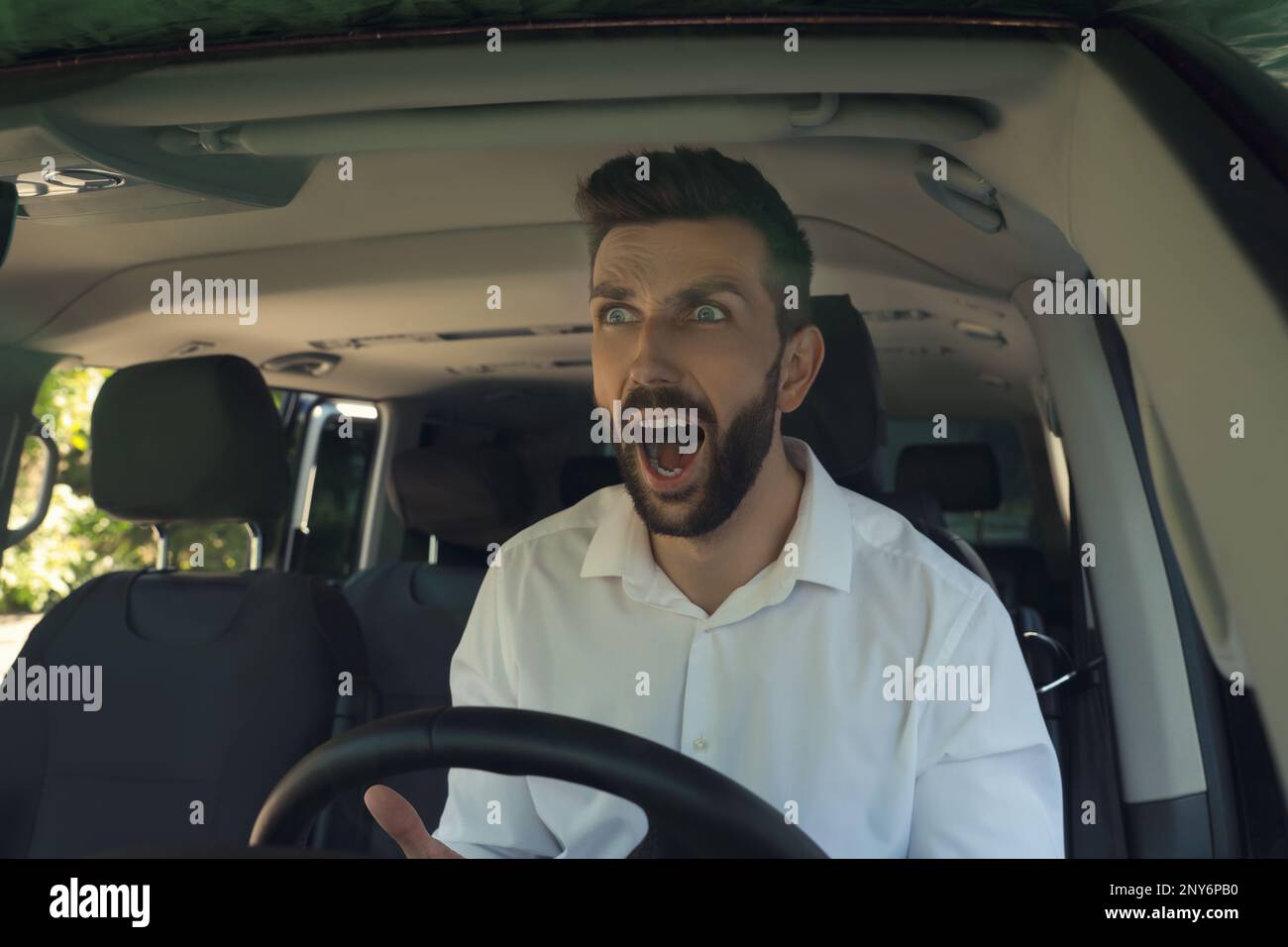 Stressed angry man in driver's seat of modern car, view through ...