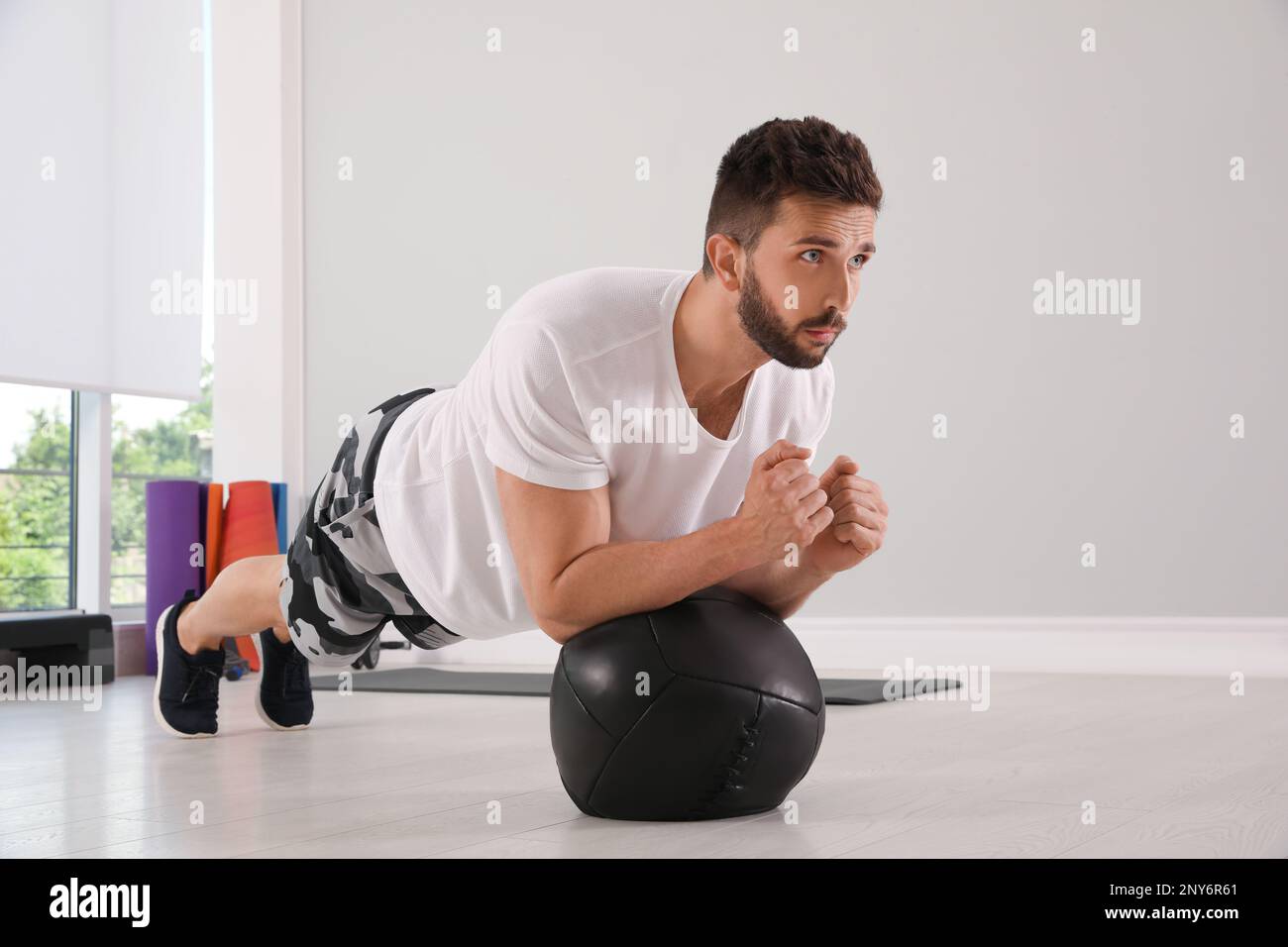 Athletic man doing plank exercise with medicine ball in modern gym ...