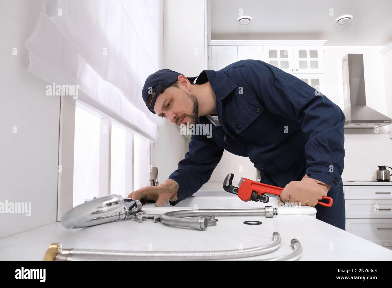 Professional plumber fixing water tap in kitchen Stock Photo - Alamy