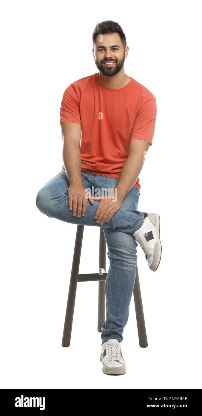 Handsome young man sitting on stool against white background Stock ...