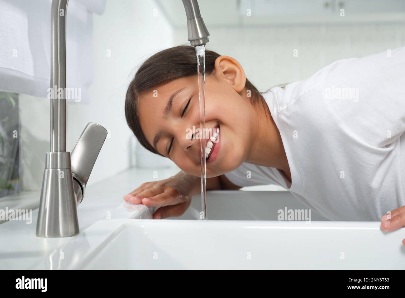 Girl drinking tap water over sink in kitchen Stock Photo - Alamy