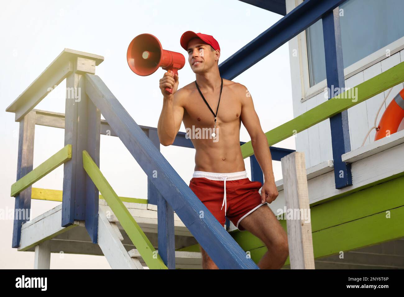 Handsome lifeguard with megaphone on watch tower against sky Stock ...
