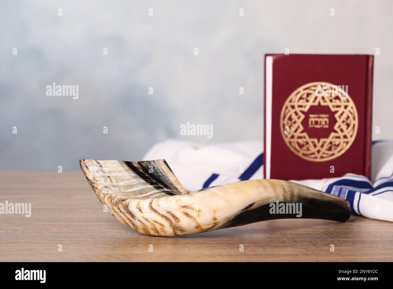 Shofar, Tallit and Torah book with text in Hebrew on wooden table ...