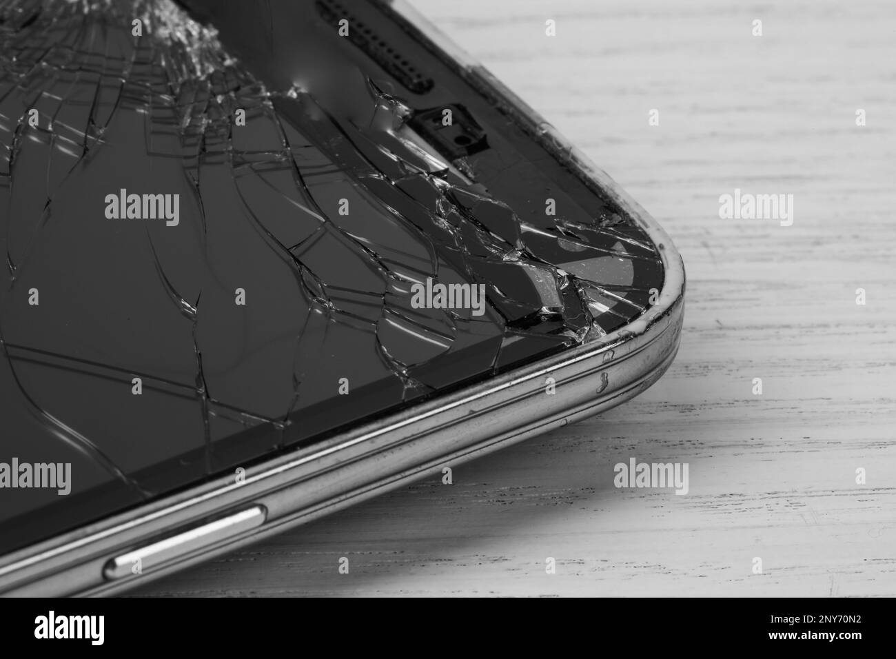 Smartphone with cracked screen on light beige wooden background ...