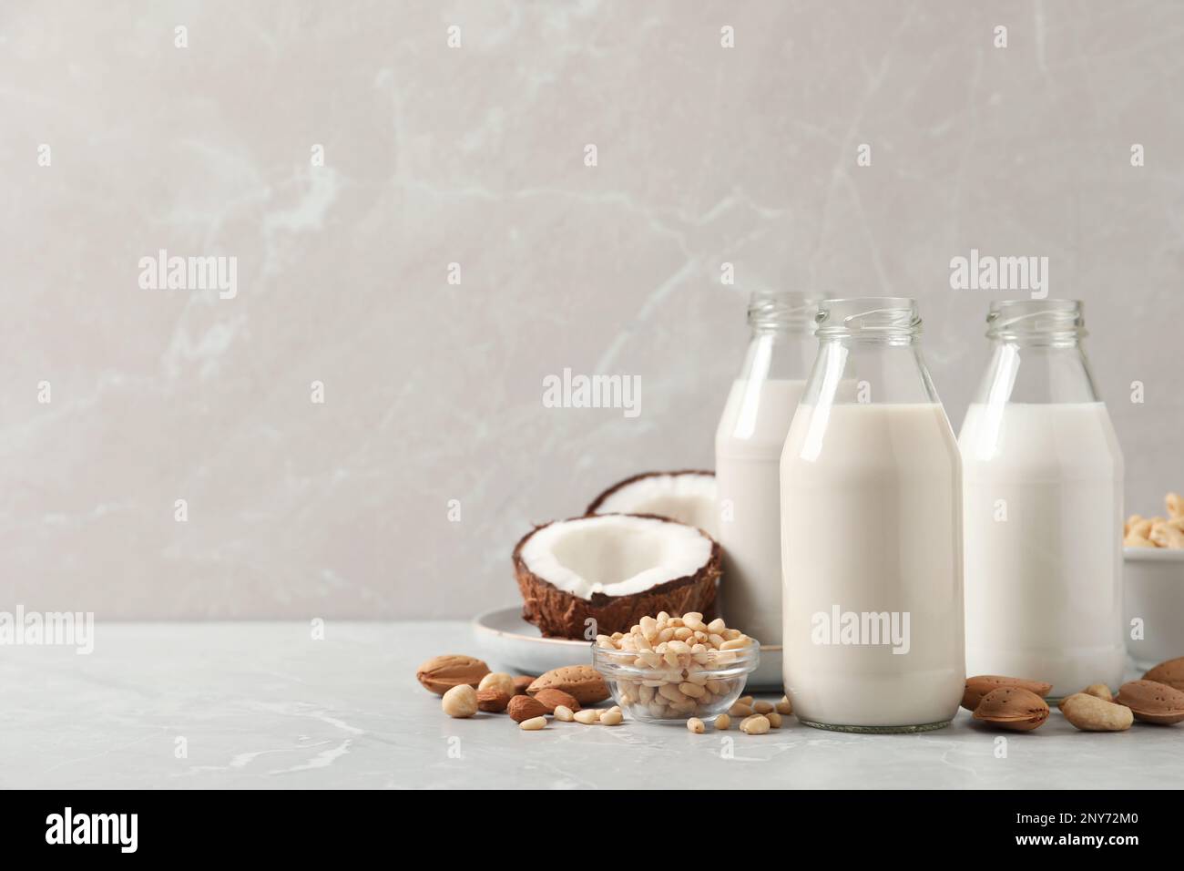 Different nut milks on light grey marble table. Space for text Stock ...