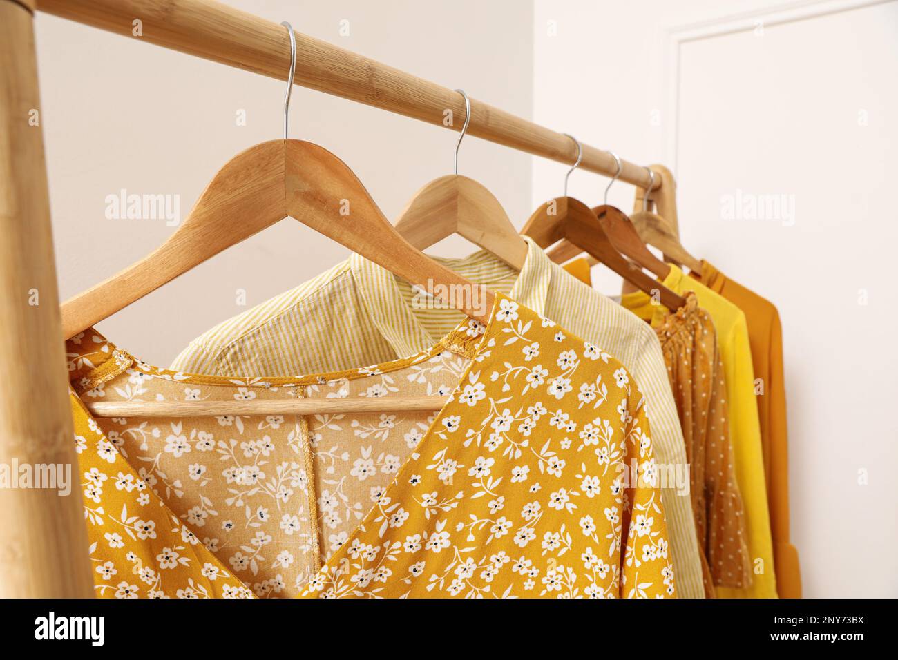 Wooden rack with hanging clothes indoors. Interior design Stock Photo ...