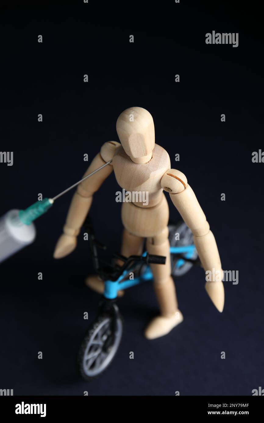 Syringe, sportsman and bike model on black background. Using doping in ...