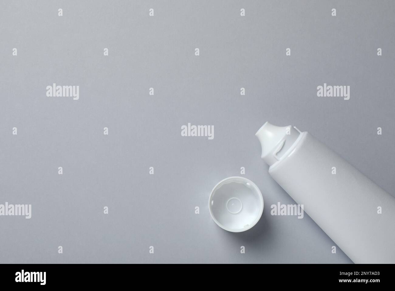 Blank tube of toothpaste on light grey background, top view. Space for ...