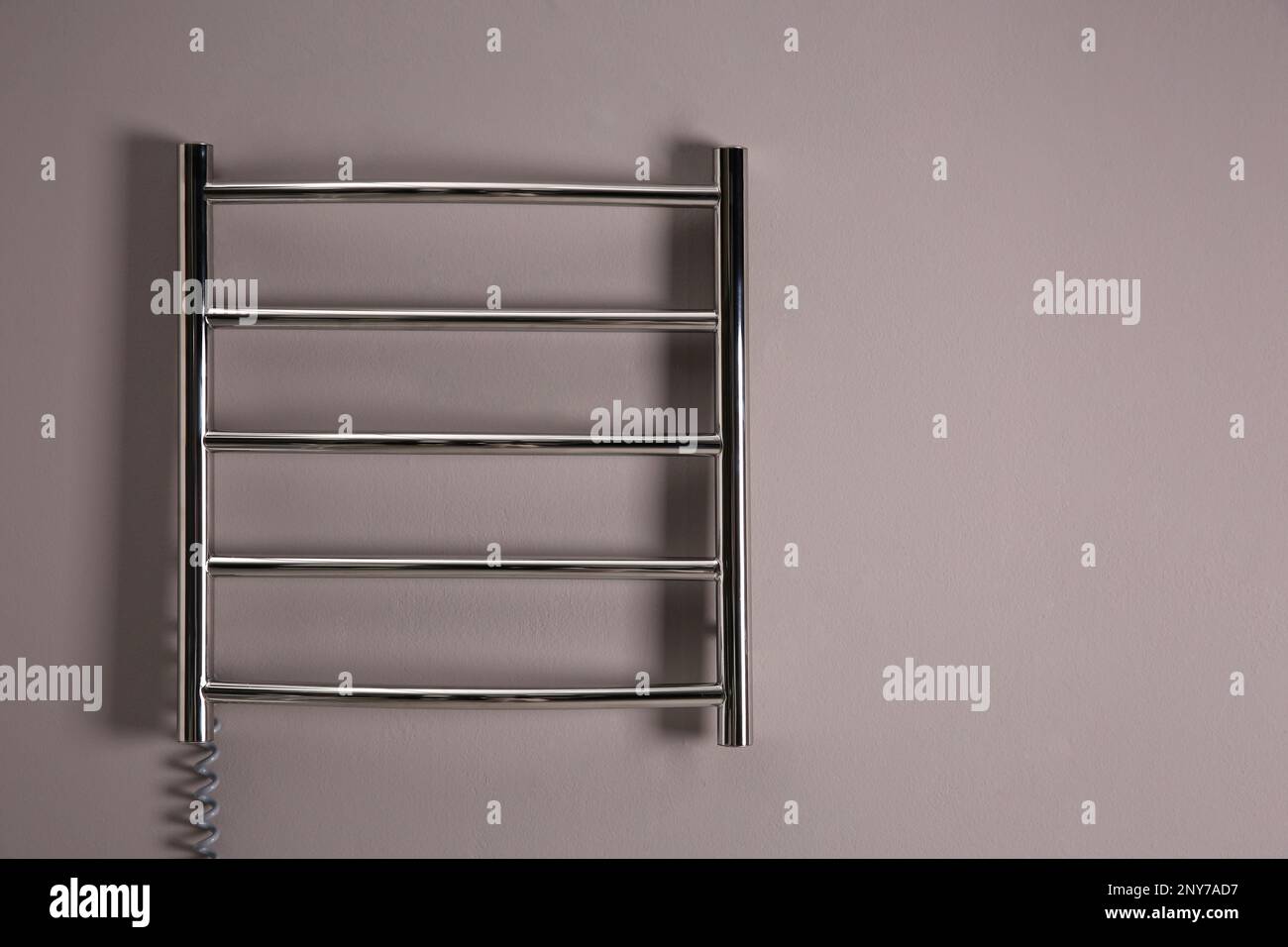 Modern heated towel rail on grey wall. Space for text Stock Photo - Alamy