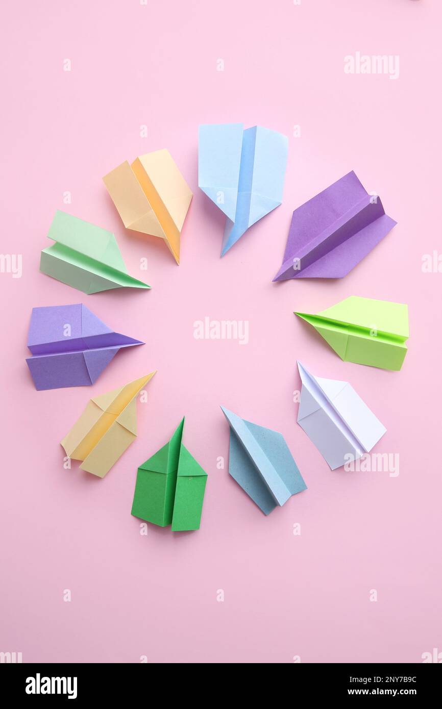 Frame of many colorful paper planes on pink background, flat lay with ...