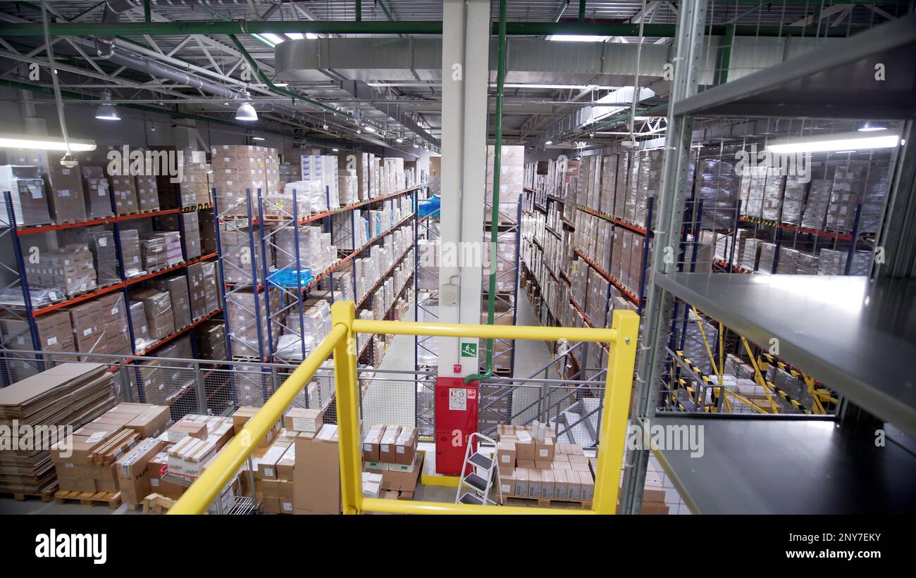 View inside of a warehouse with many rows of metal shelves and goods ...