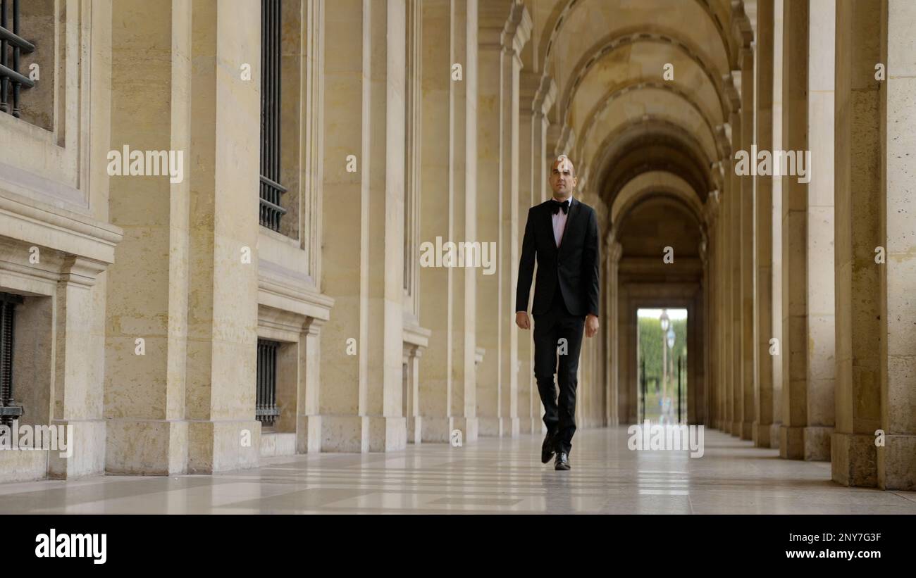 Man in black and white official suit walking in arcuate shaped hall ...