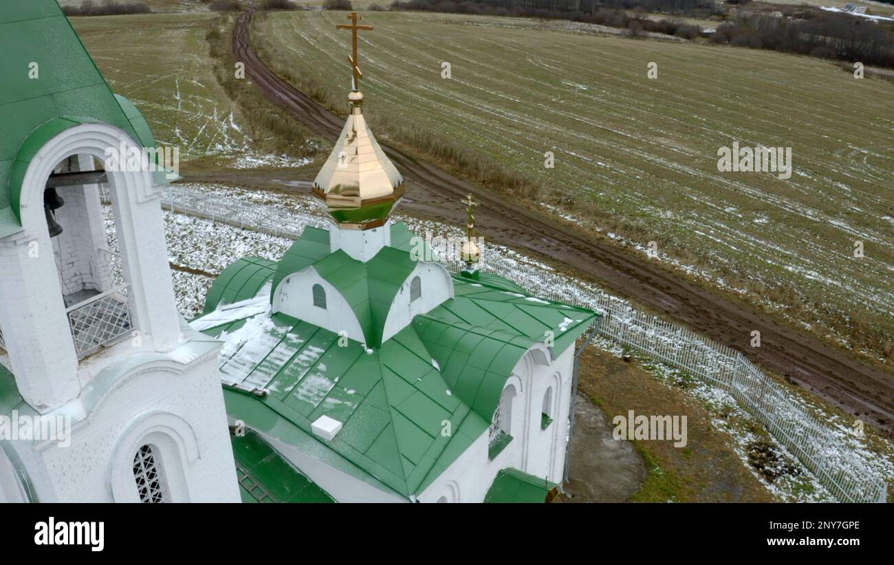 Aerial view of a white and green church with a golden cross and bell ...