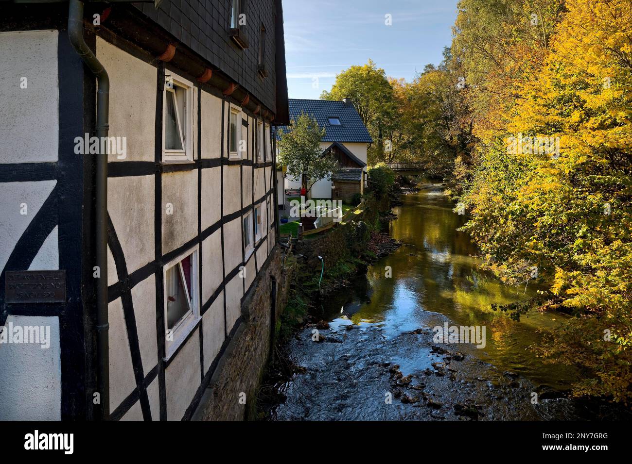 Half-timbered house with the river Roehr in Hachen with a marker for ...