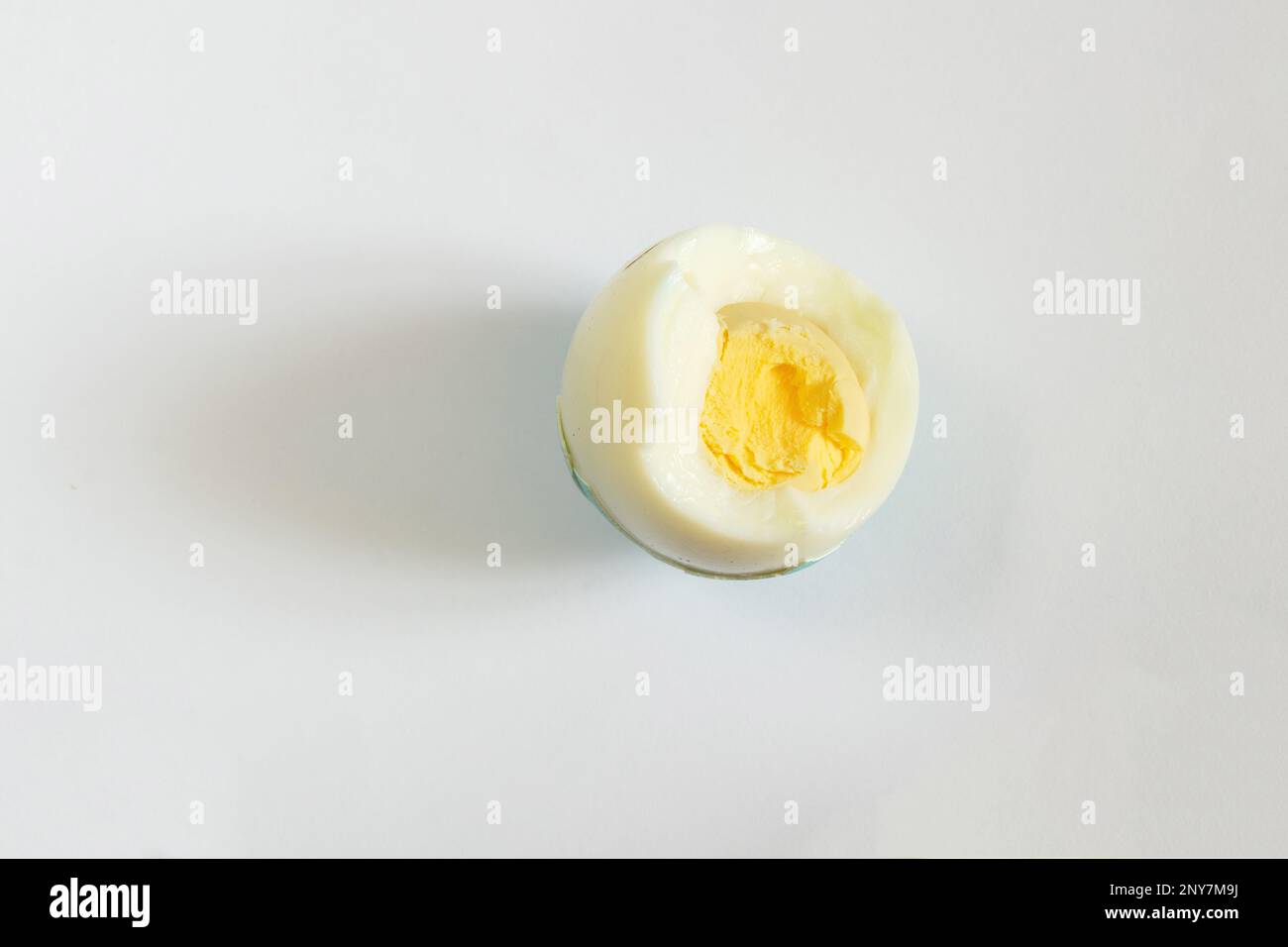 a bite of a boiled egg in the shell lies on a white background Stock ...