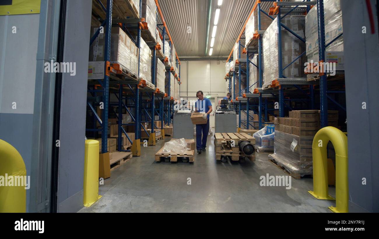 Serbia - Belgrade, September 20, 2022: Workers using pallet truck along ...