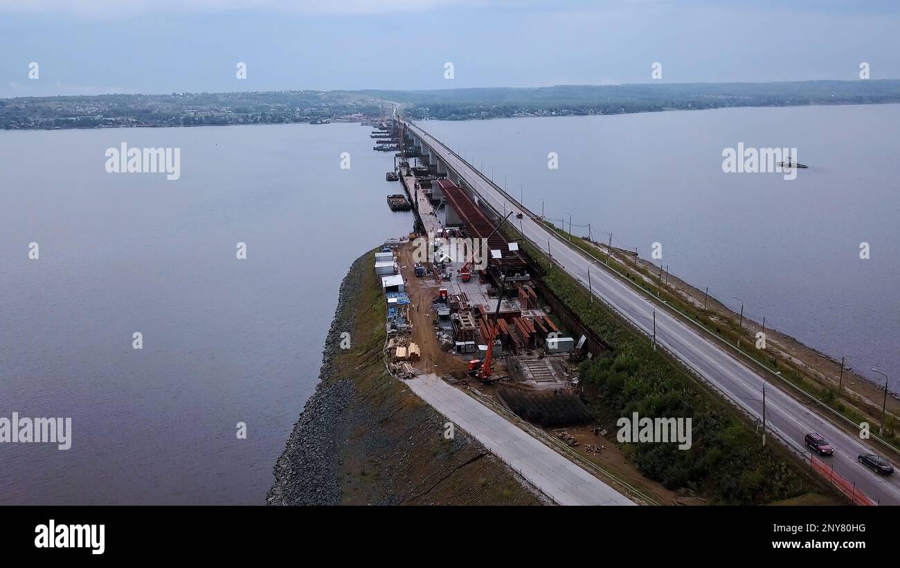 Aerial view of a wide river or lake crossed by the long narrow bridge ...