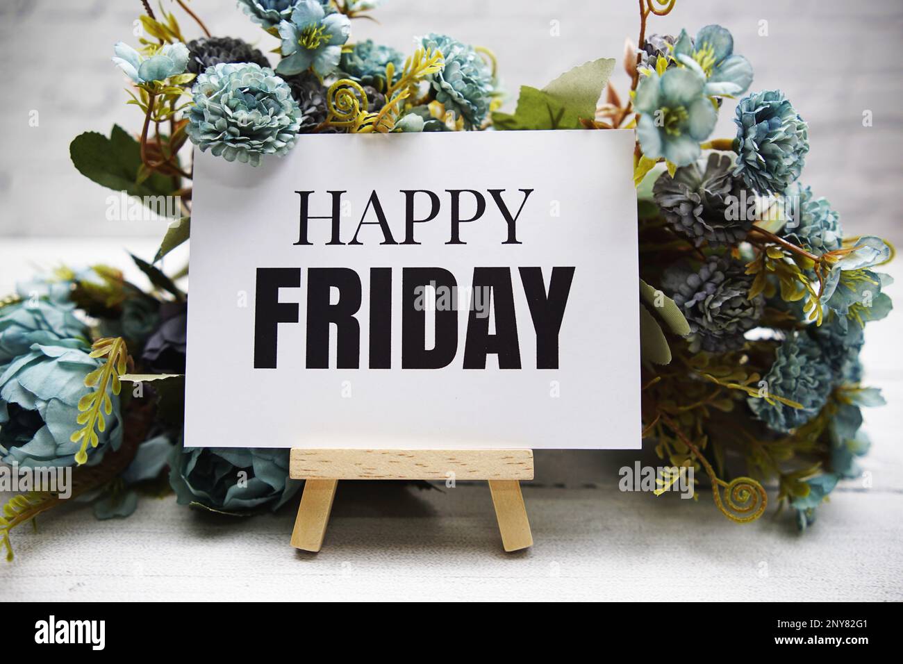 Happy Friday text on wooden easel standing on white brick wall and ...