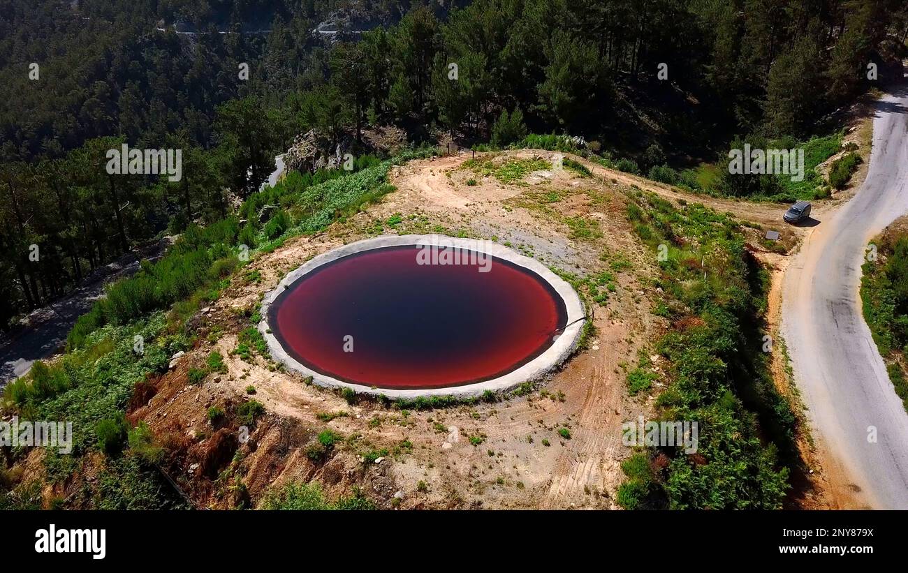 Aerial view of a round shaped red lake located at the edge of a green ...