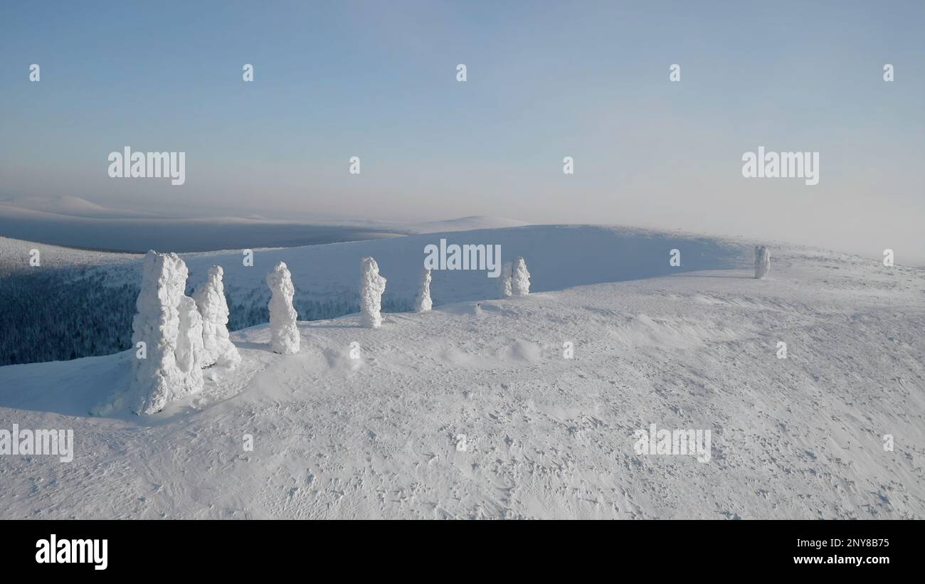 Flying above snow covered unusual pillars on a clear blue sky ...