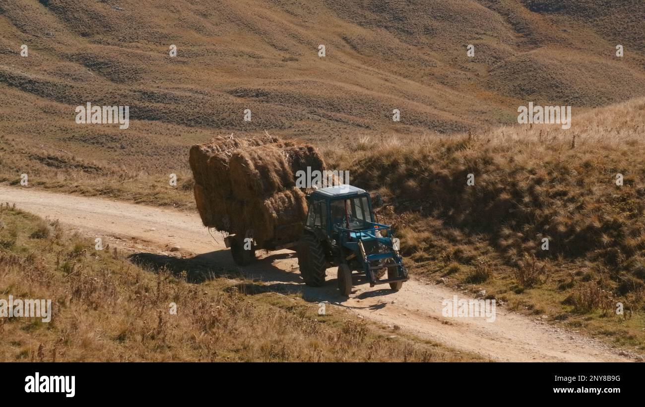 Vehicle loaded by haystacks passing at rural area. Creative. Sunny day ...