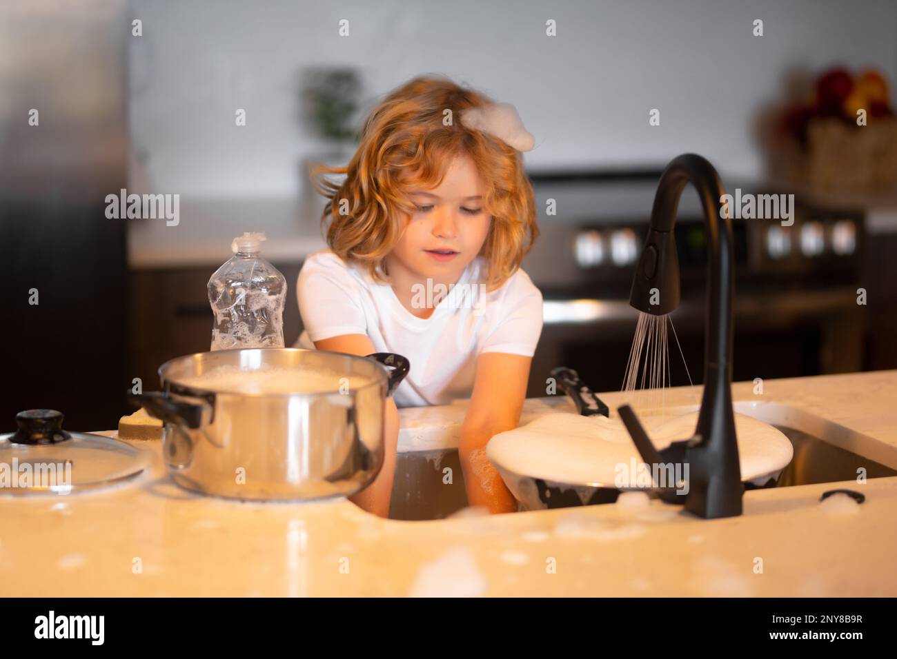 Child boy washing dishes in the kitchen interior. Cleaning dishwashing ...