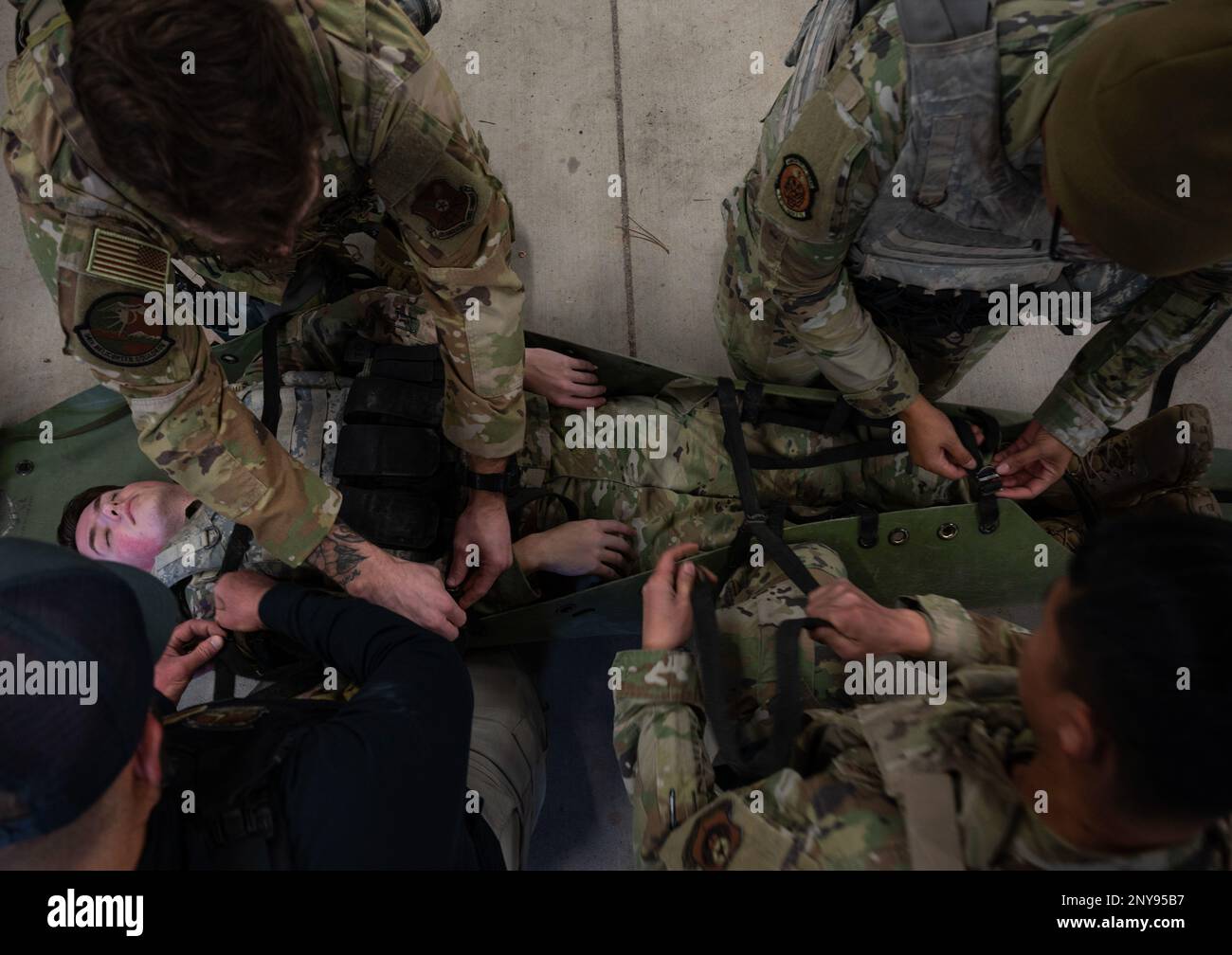 U.S. Air Force Airmen secure a simulated patient to a medical litter in preparation for ...