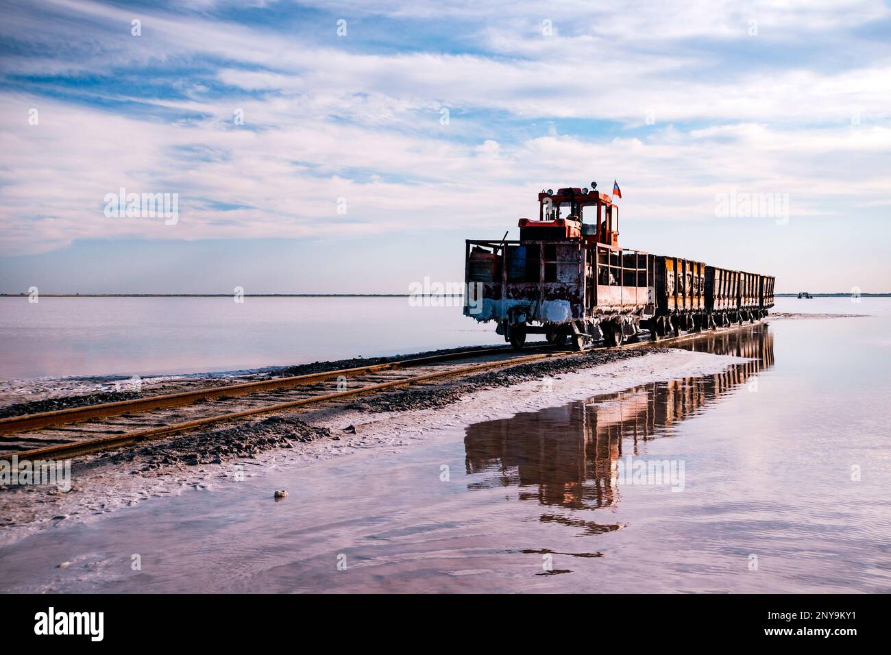 Old train rides on the railway laid in the water through the salt lake. train travels from water ...