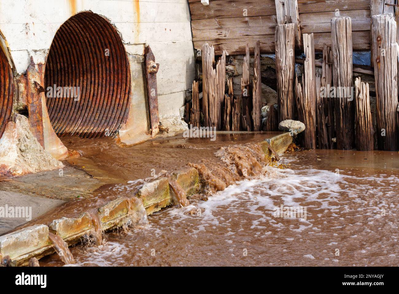 Malibu beach drainage system with large rusty pipe ducts and running ...