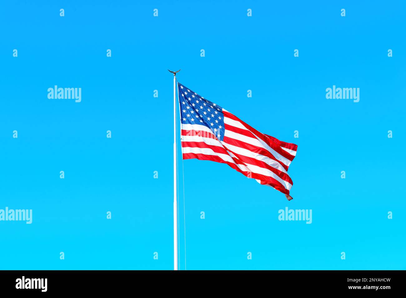 American flag in motion waving freely against a clear blue sky ...