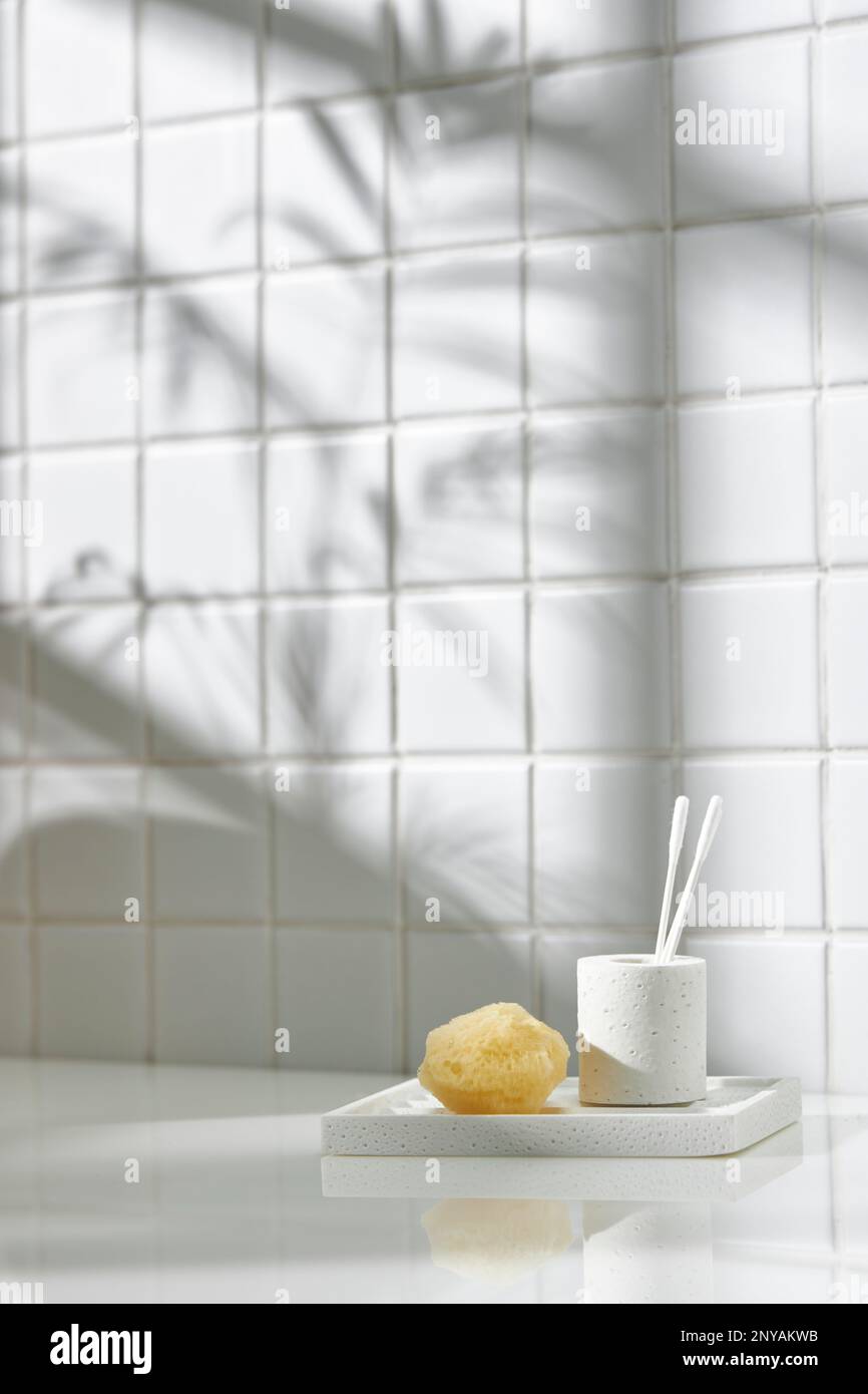Various objects on a white tile background with warm sunlight shining ...