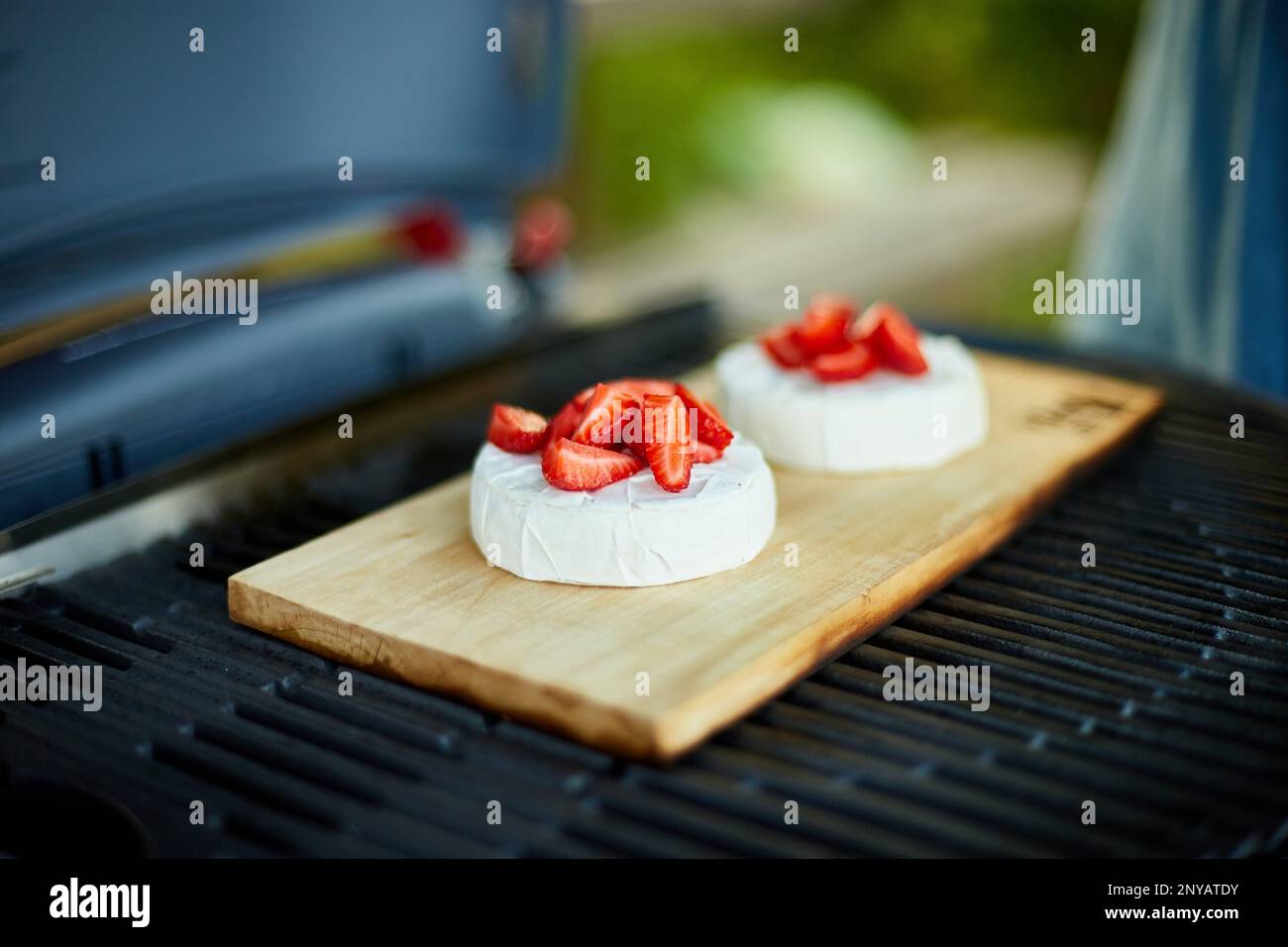 Woman hand put strawberry on grill camembert cheese outdoor, on ...