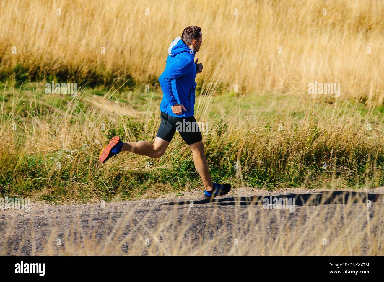 male runner running on road among dry grass Stock Photo - Alamy