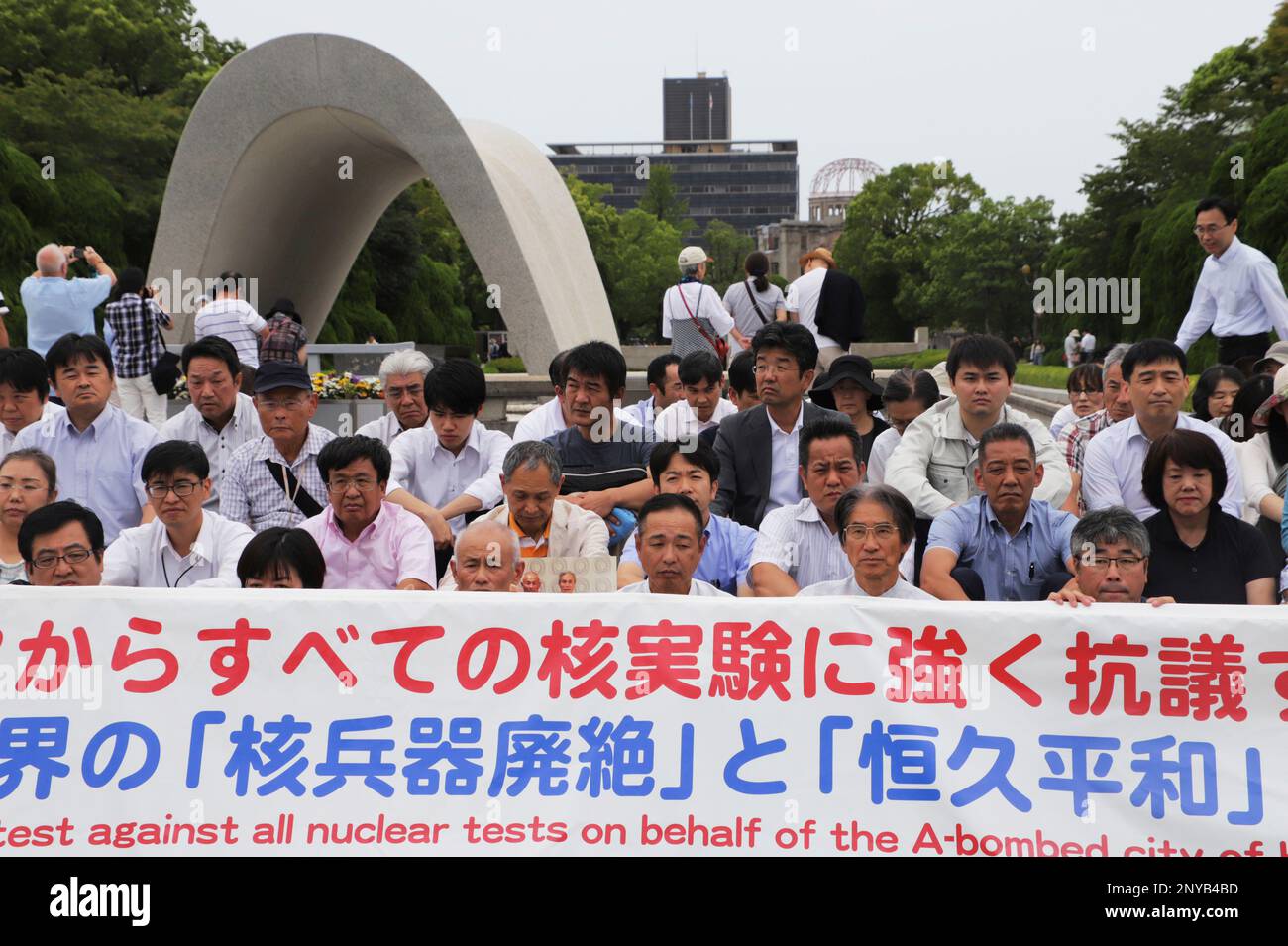 People including atomic-bomb victim sit and hold a banner to protest ...