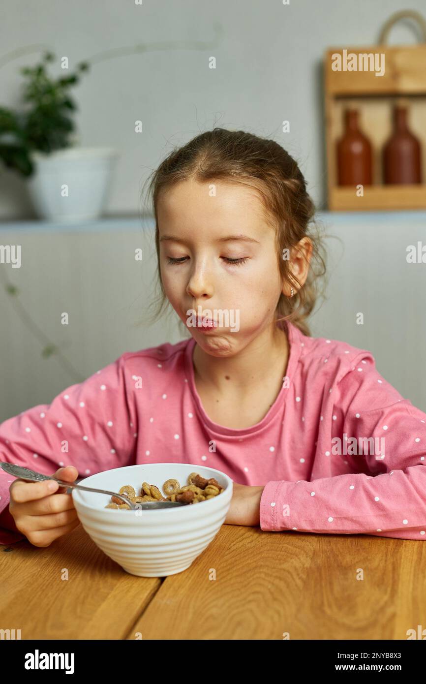 Cute little girl enjoy eating cereal with milk for morning breakfast ...