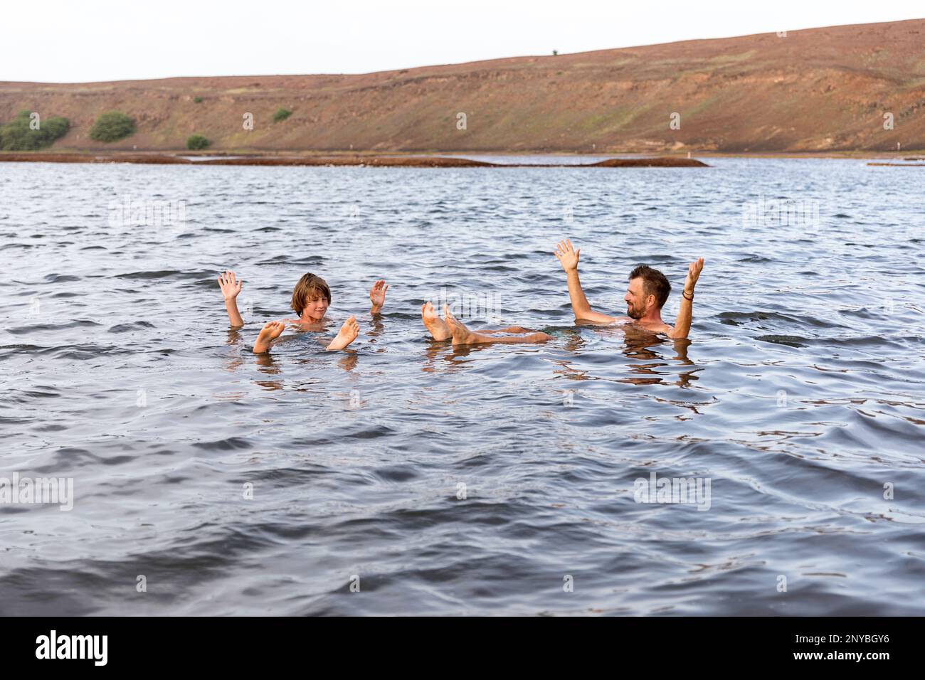 Father and son, tourists, swimming in a lake in Spectacular salt pans ...