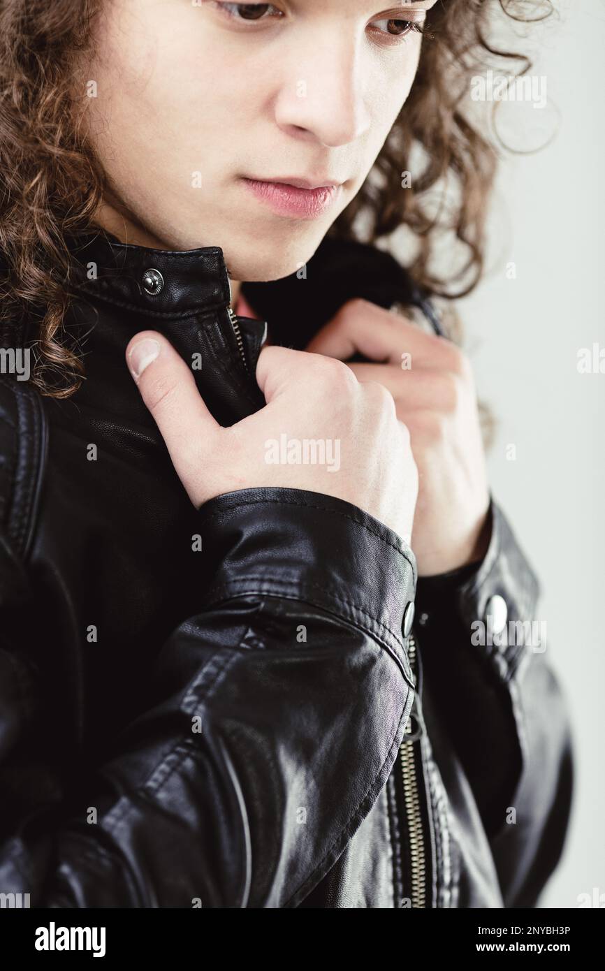 Sad or absorbed look of young man with long wavy hair and a leather ...