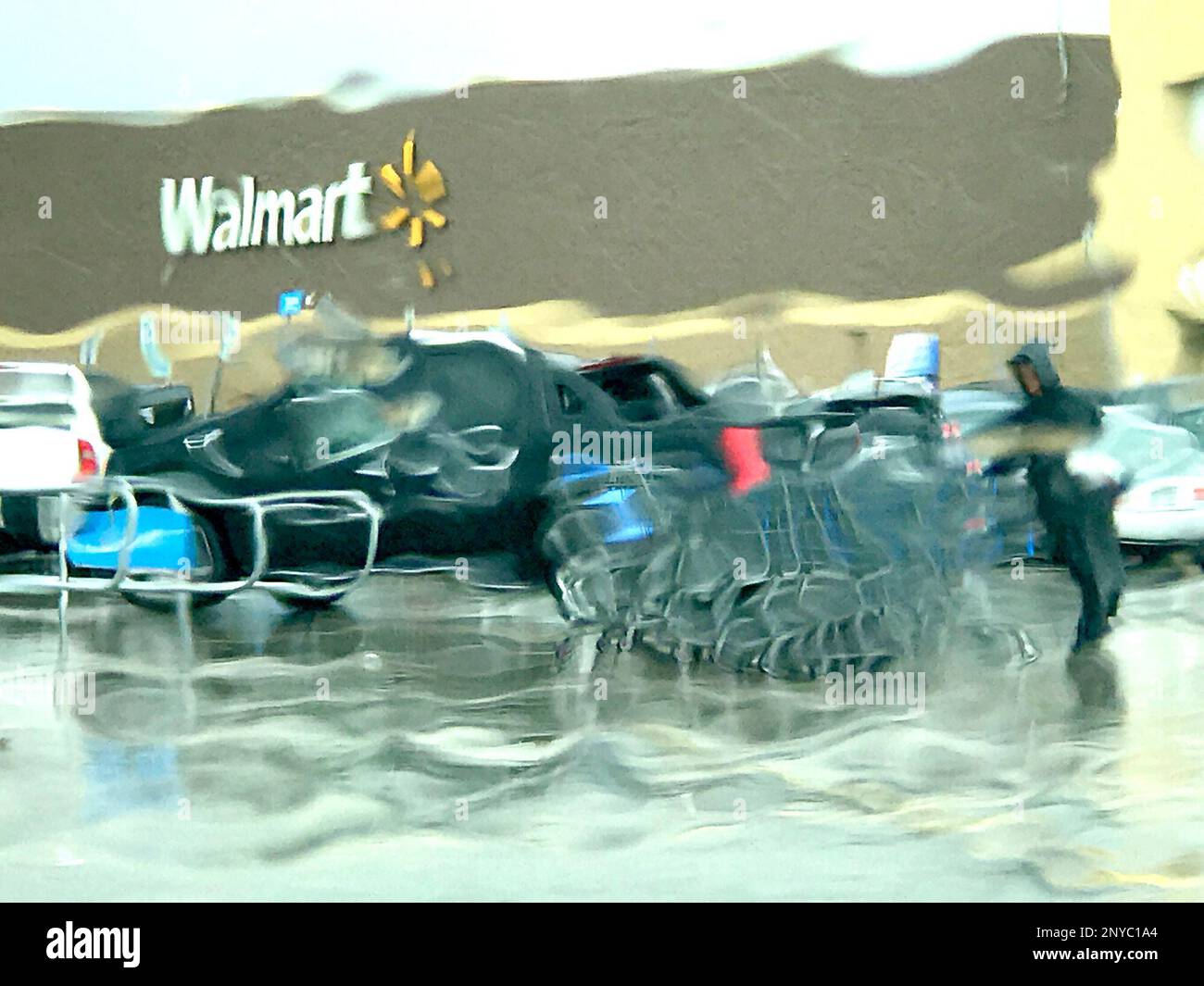 Seen through a rain-streaked windshield, a Walmart employee corrals ...