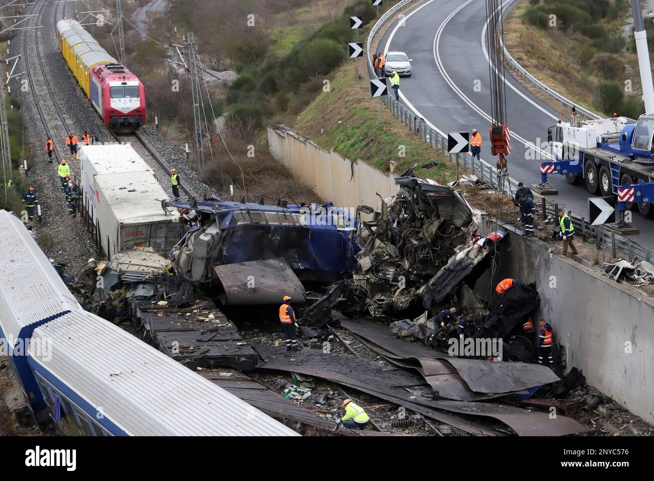Workers operate a crane as they try to remove debris from the rail ...