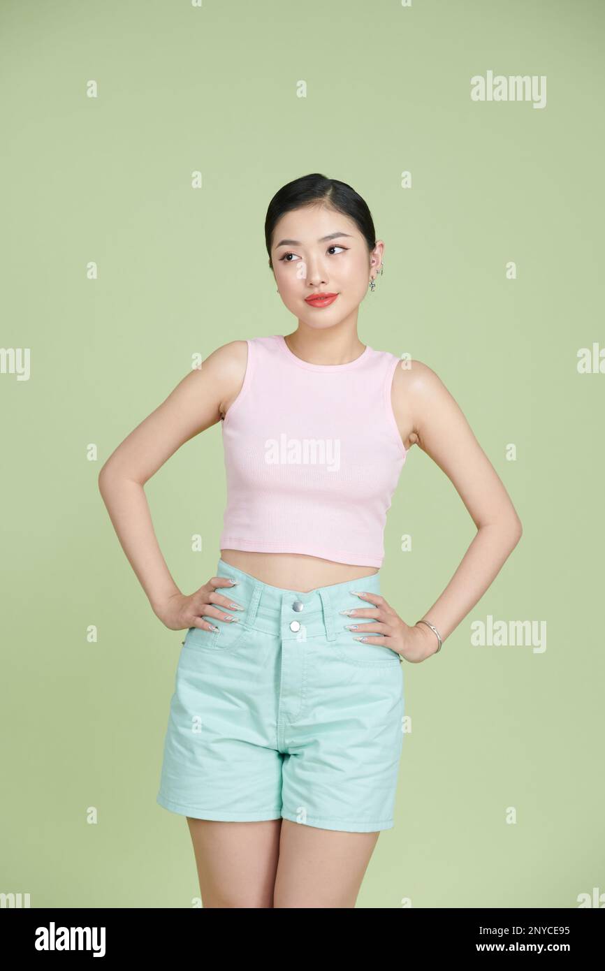 happy smiling young woman with hands on hips posing over green ...