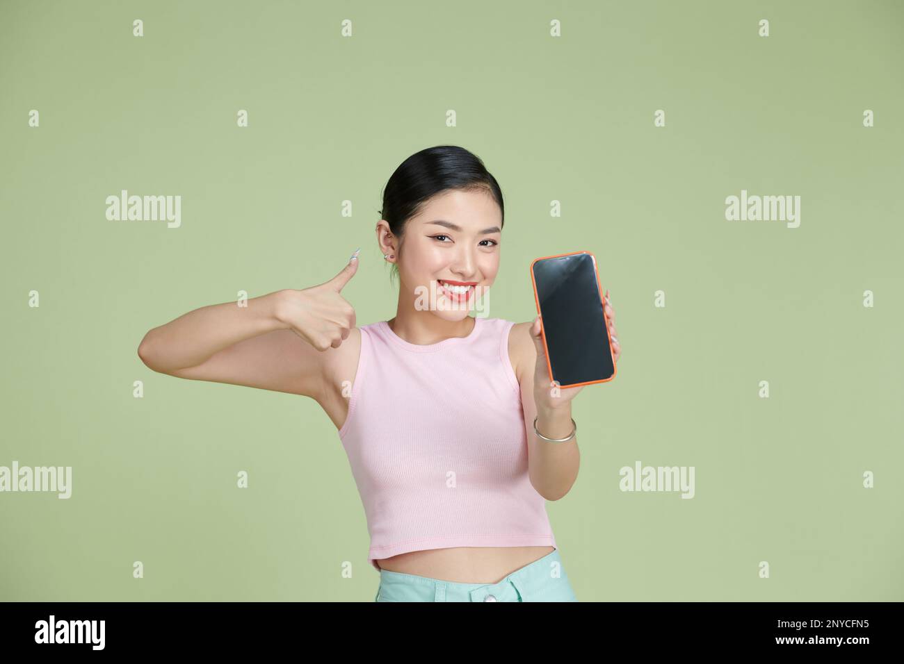 Portrait of smiling asian woman holding smartphone with black blank ...