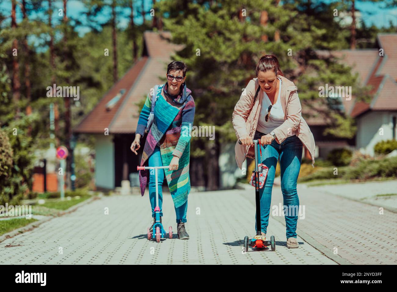 Two women having fun in the park while riding a scooter Stock Photo - Alamy