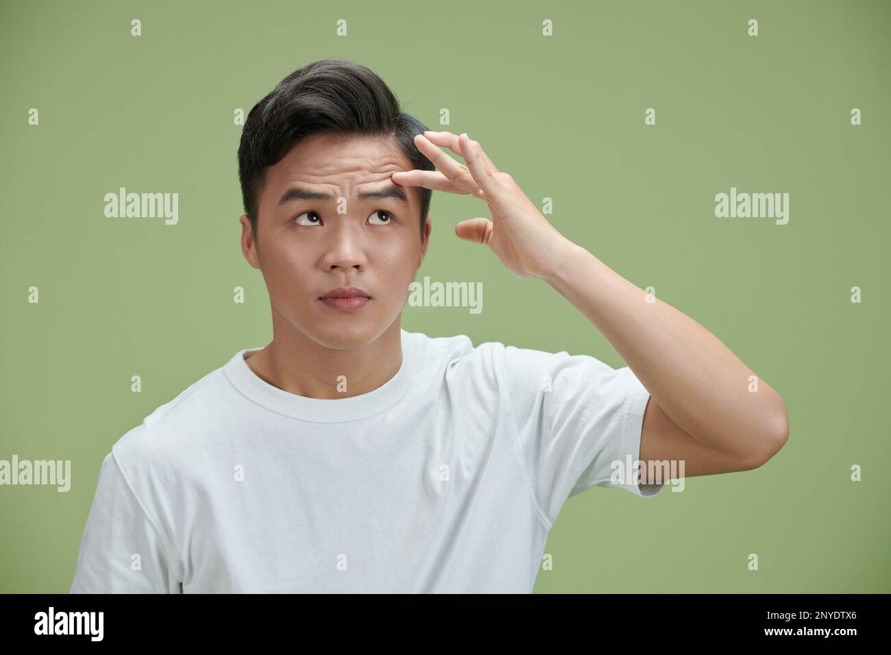 Anti aging. Handsome young man touching his forehead while standing ...