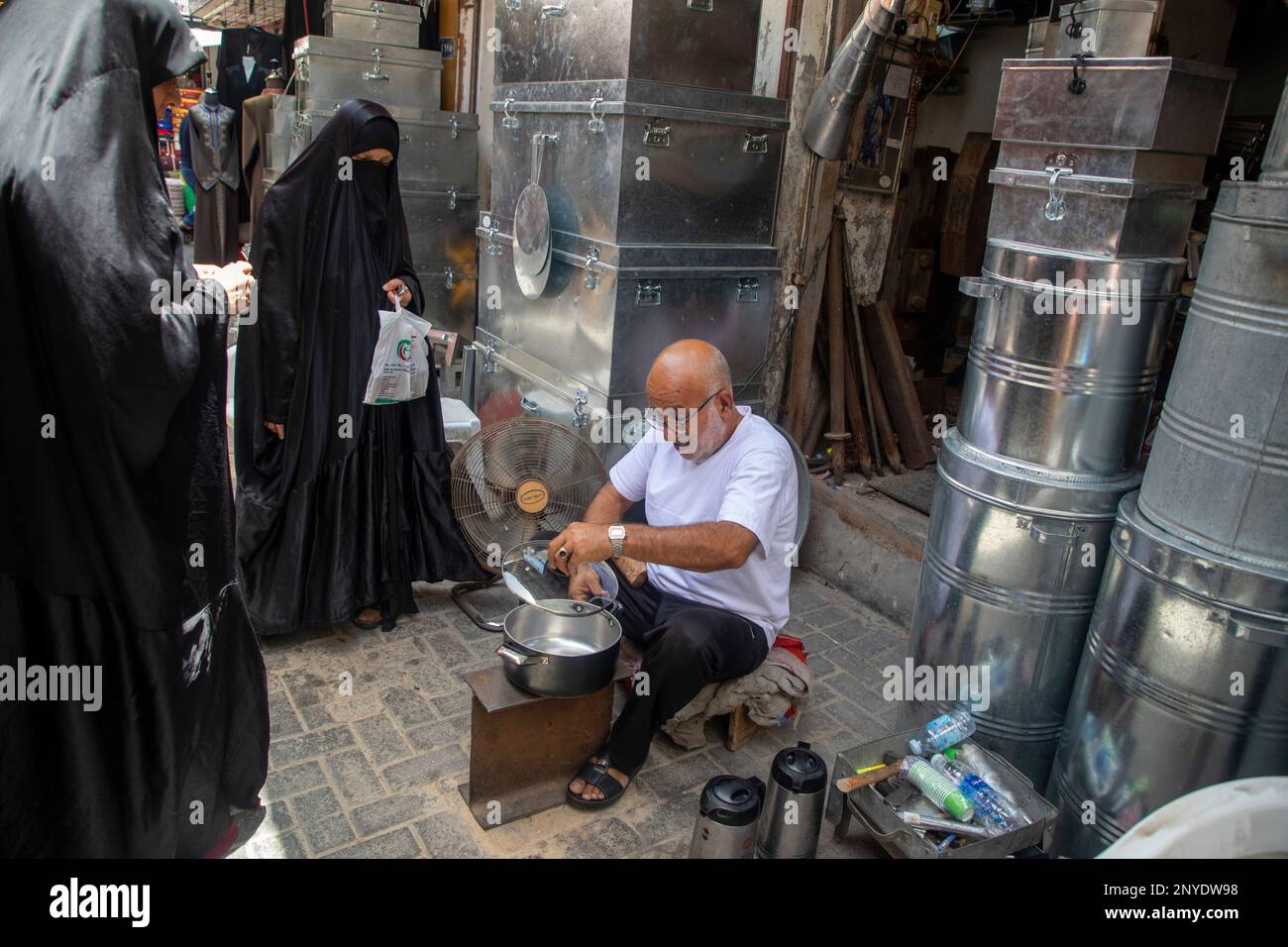 A Bahraini old man repairs crockery outside his shop at the Bab al ...
