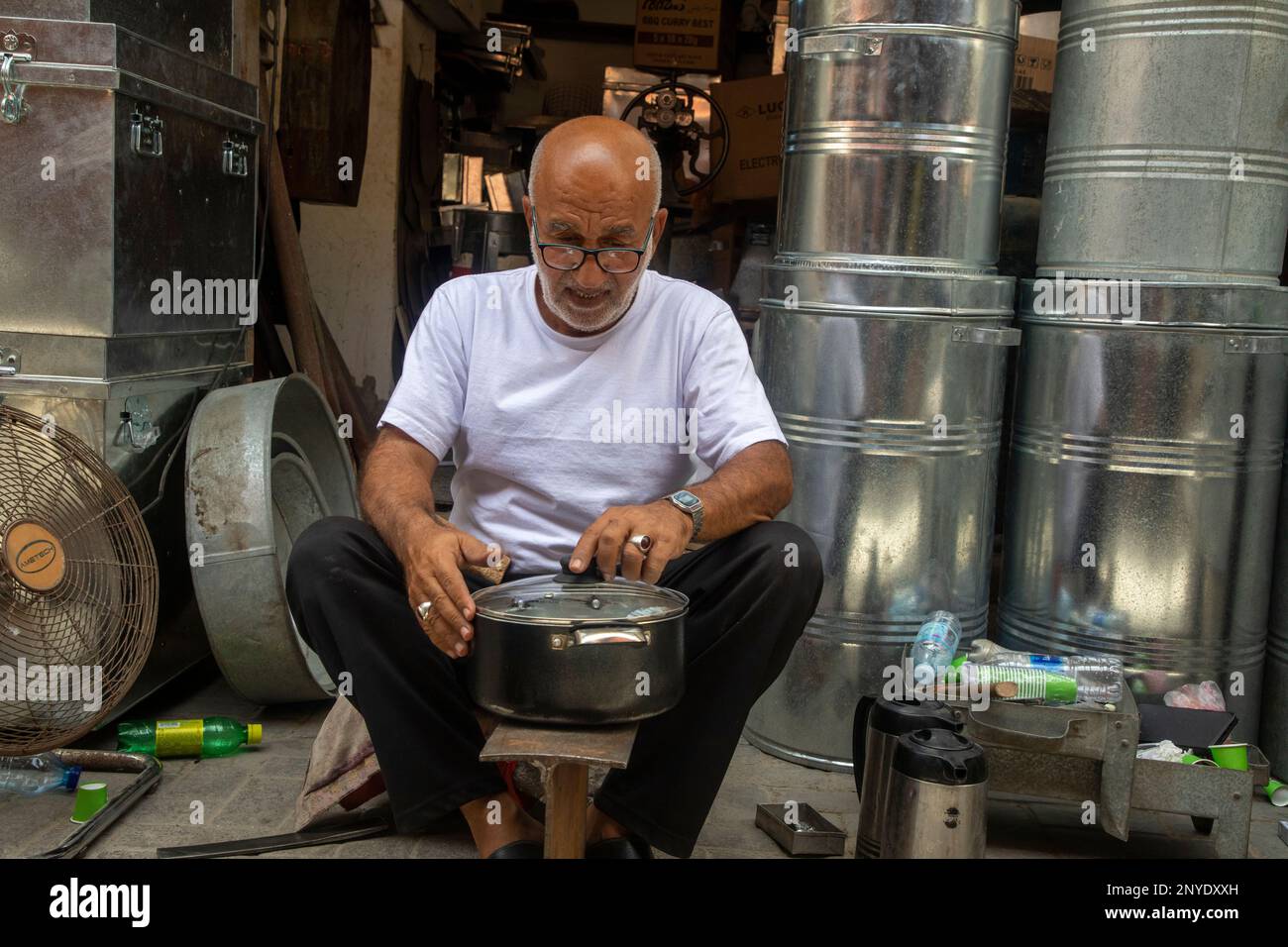 A Bahraini old man repairs crockery outside his shop at the Bab al ...